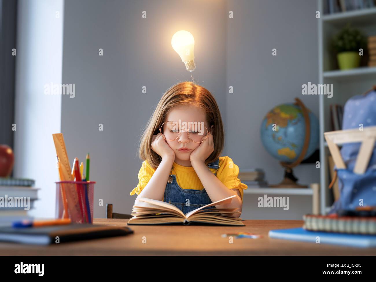 Back to school. Thinking child is sitting at desk. Girl doing homework ...