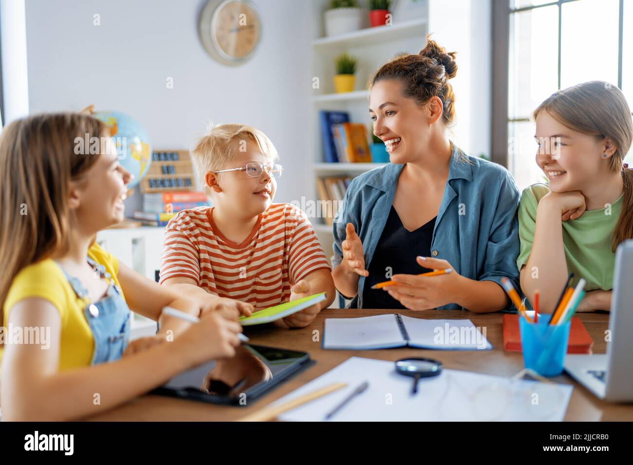 Happy kids and teacher at school. Woman and children are talking in the ...