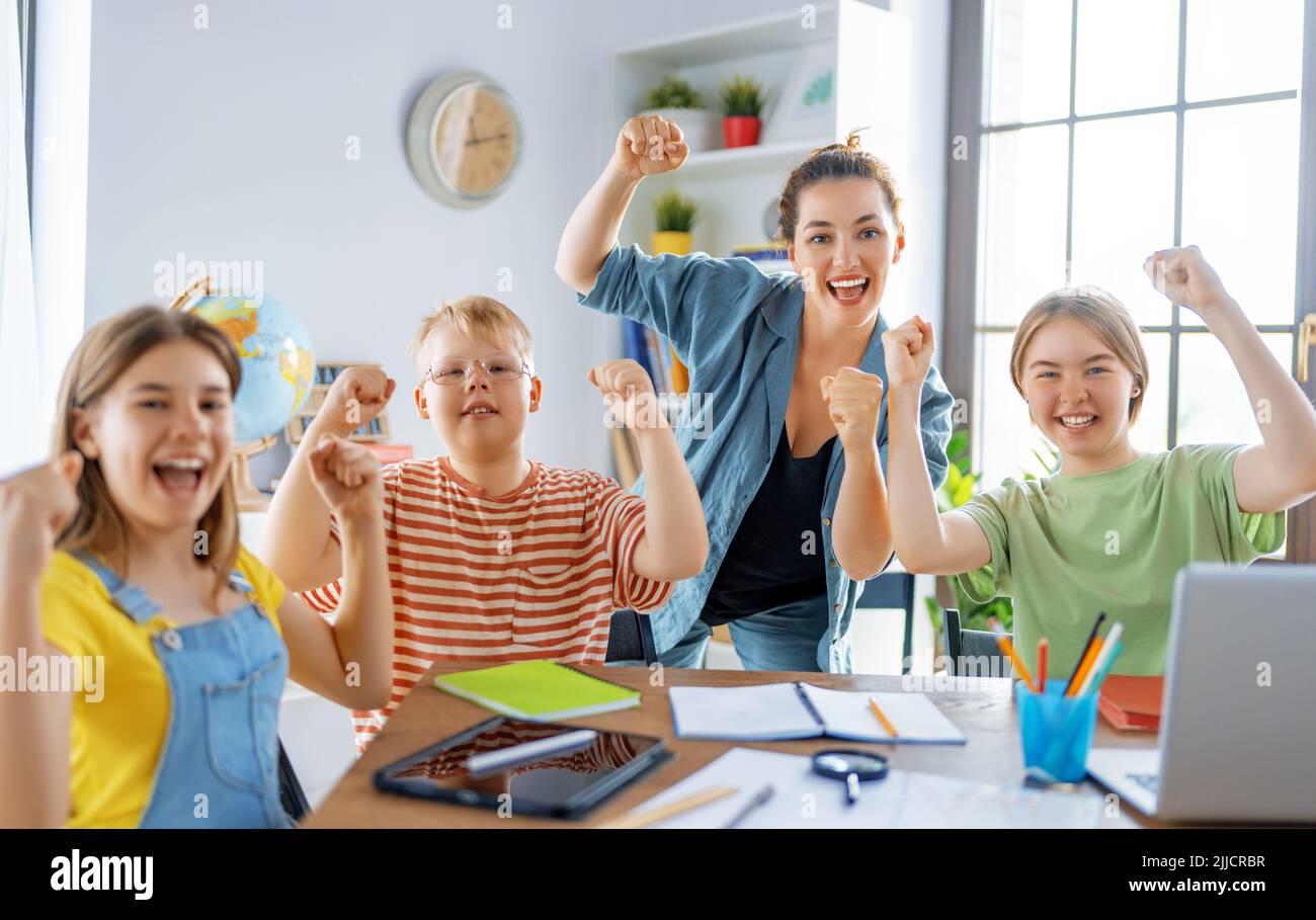 Happy kids and teacher at school. Woman and children are talking in the ...
