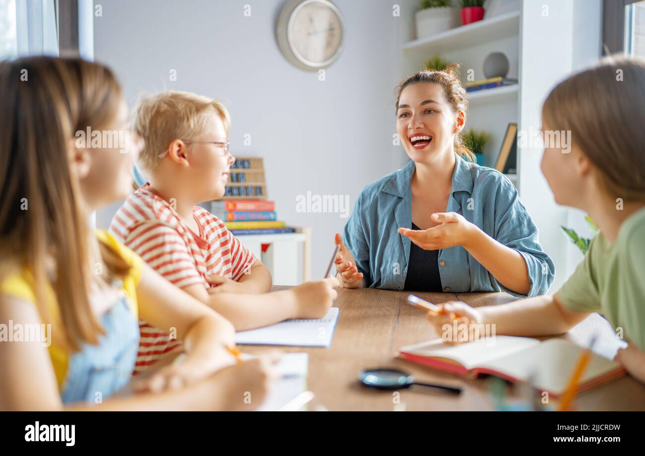 Happy kids and teacher at school. Woman and children are talking in the ...