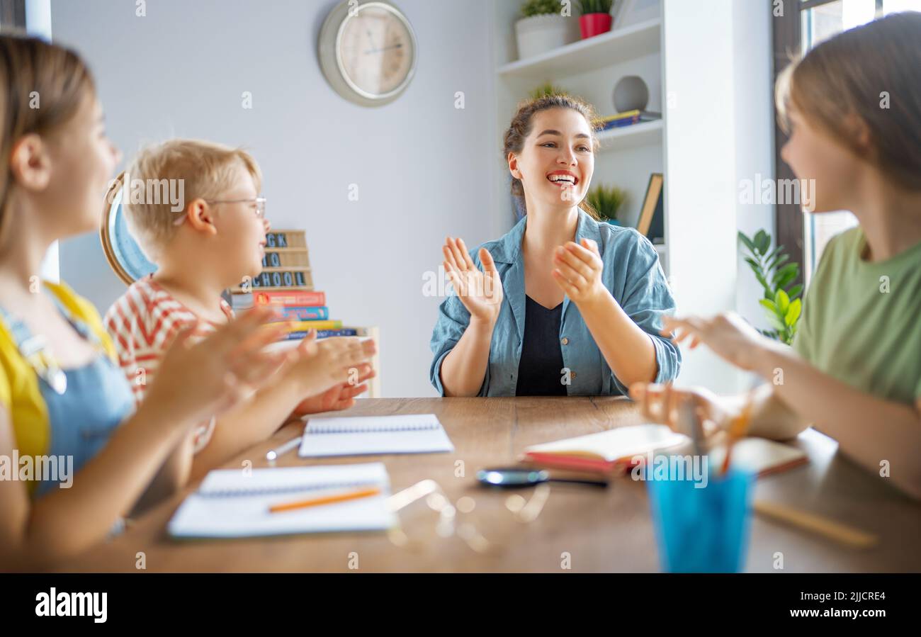 Happy kids and teacher at school. Woman and children are talking in the ...
