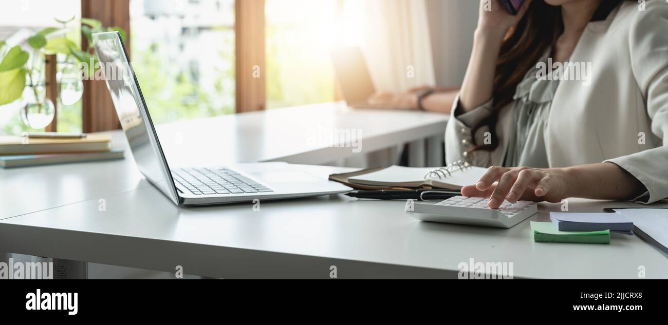 Woman accountant using calculator and computer in office panoramic ...