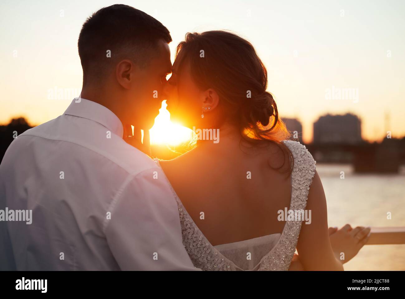 A kiss of the bride and groom at sunset. Wedding article. A happy ...