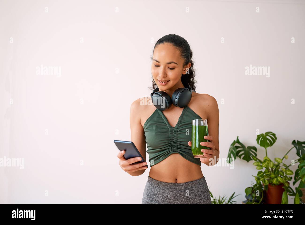 A young multi-ethnic woman tracks yoga session on fitness app with ...