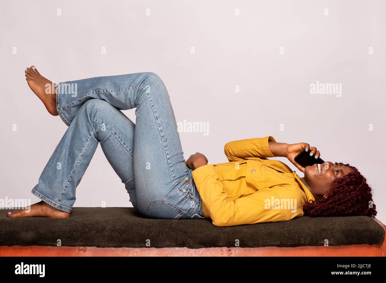 black lady lying on a bench making a phone call smiling Stock Photo - Alamy