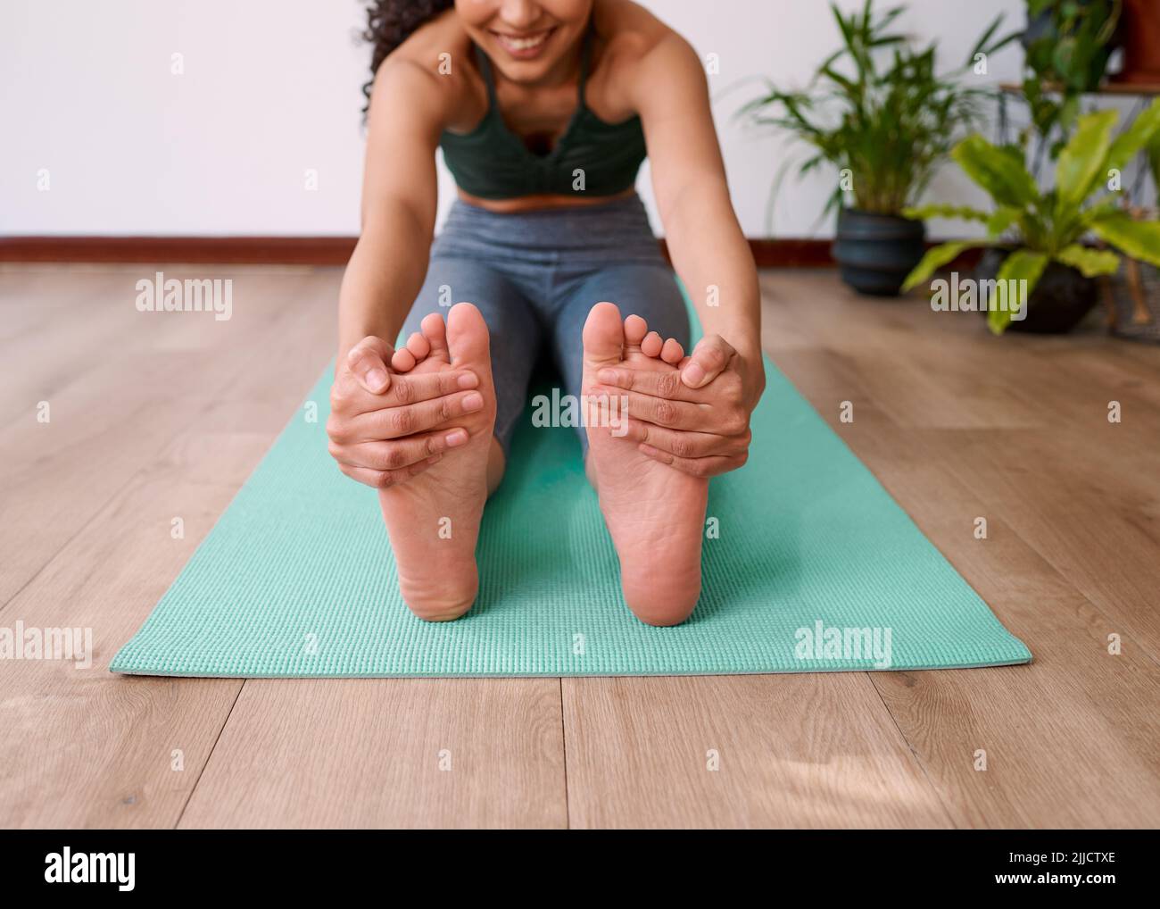 Close up of feet while young multi-ethnic woman stretches on yoga mat ...