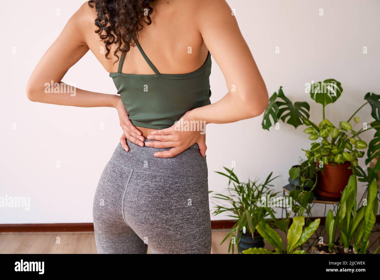 A young multi-ethnic woman holds her back in pain during yoga Stock ...