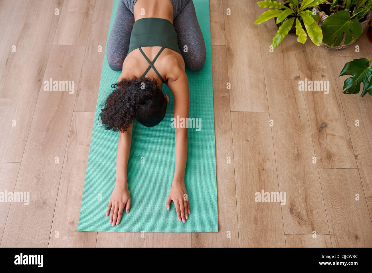 A young multi-ethnic woman rests in child's pose on yoga mat - cropped ...
