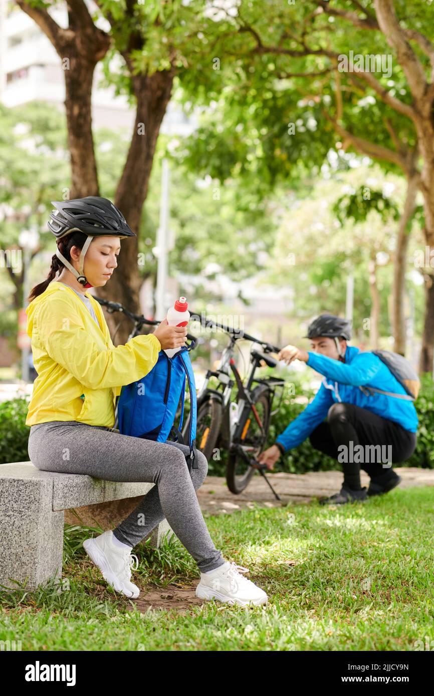 Woman taking vitamin water out of backpack when her boyfrirnd adjusting ...