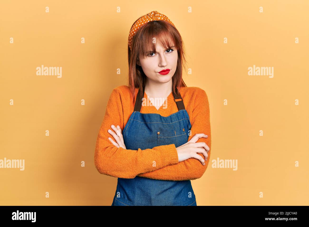 Redhead young woman wearing apron skeptic and nervous, disapproving ...