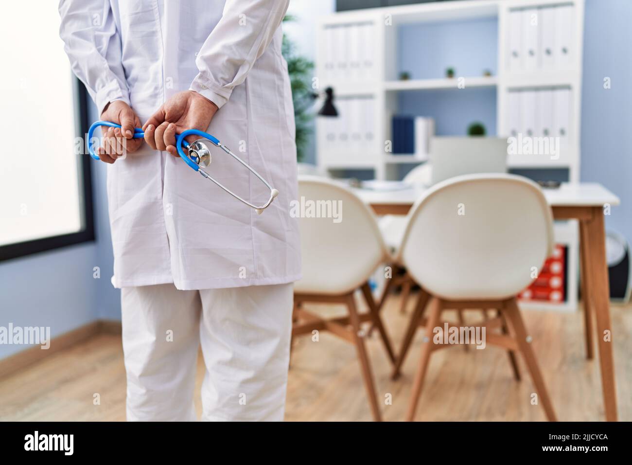 Young redhead man wearing doctor uniform on back view holding ...