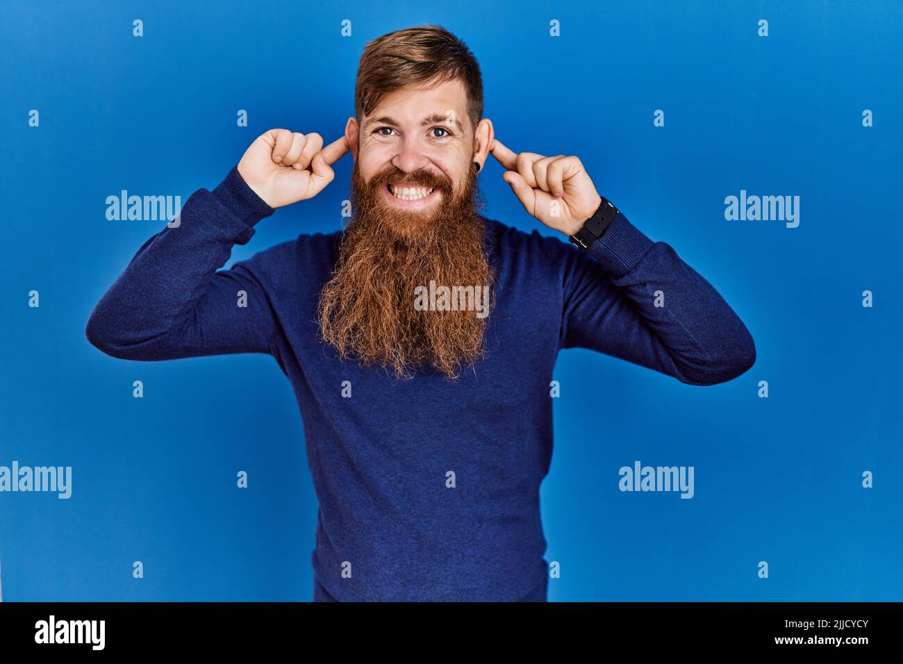 Redhead man with long beard wearing casual blue sweater over blue ...