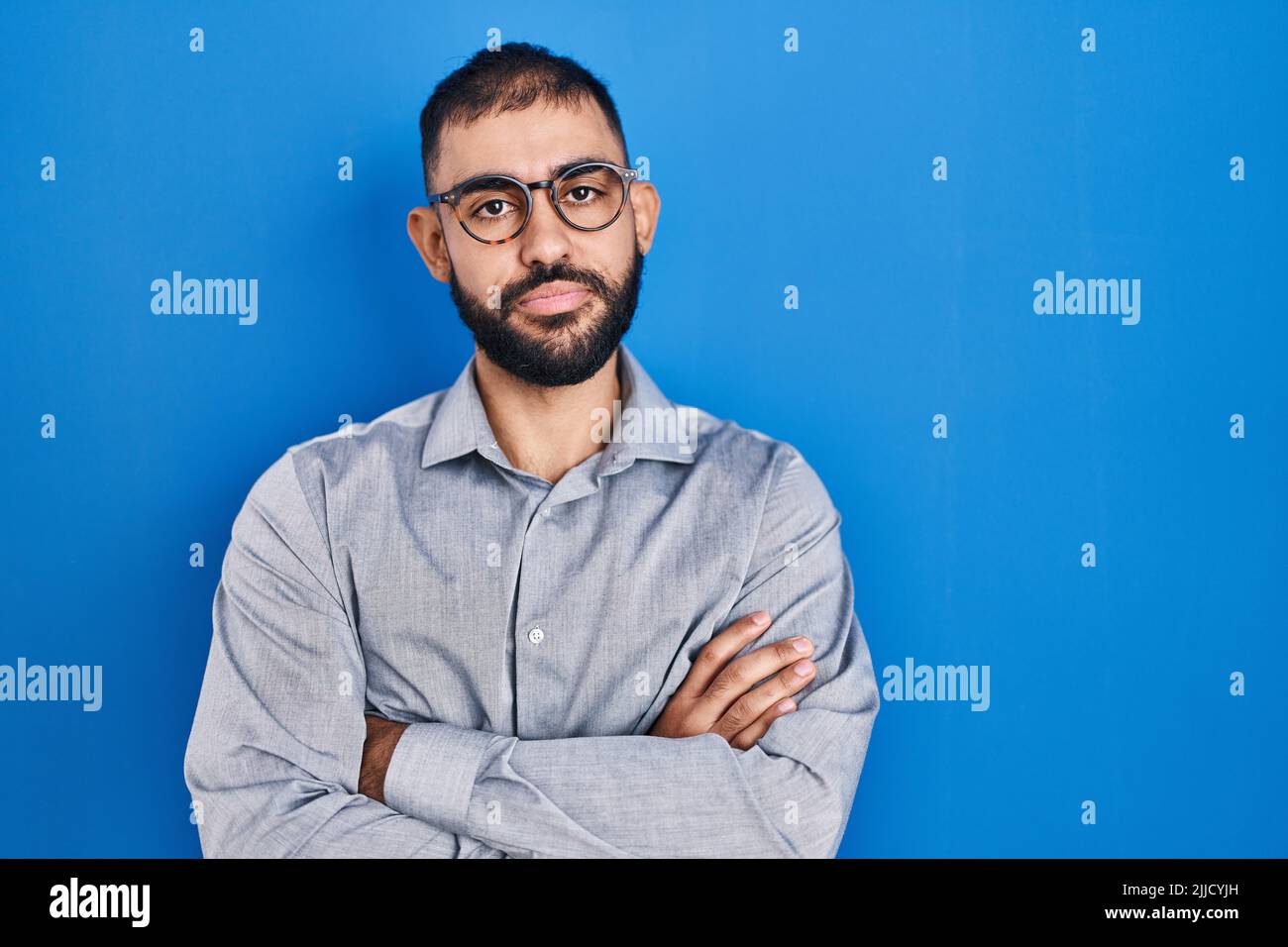 Middle east man with beard standing over blue background smiling ...
