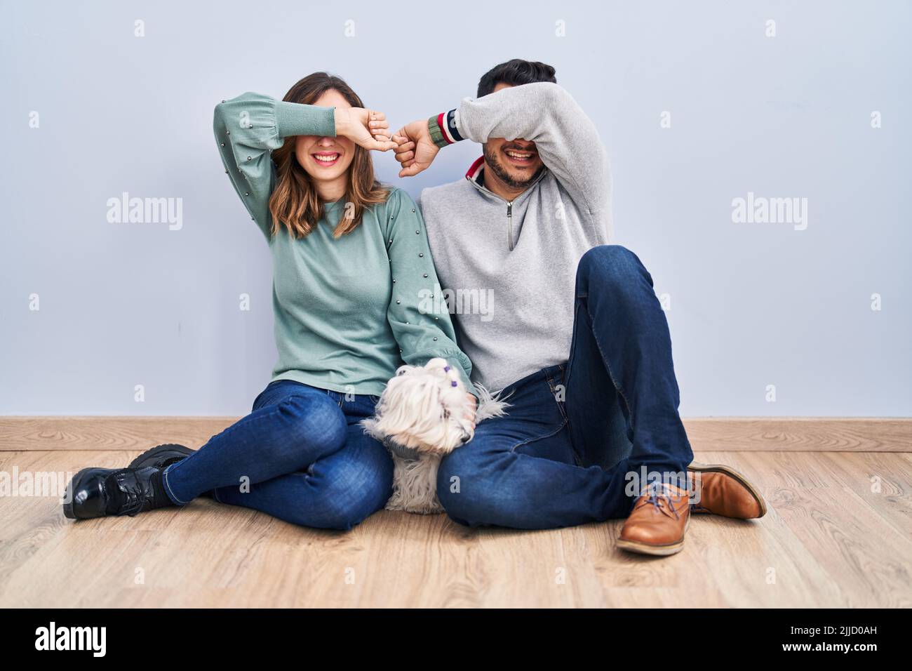 Young hispanic couple sitting on the floor with dog smiling cheerful ...