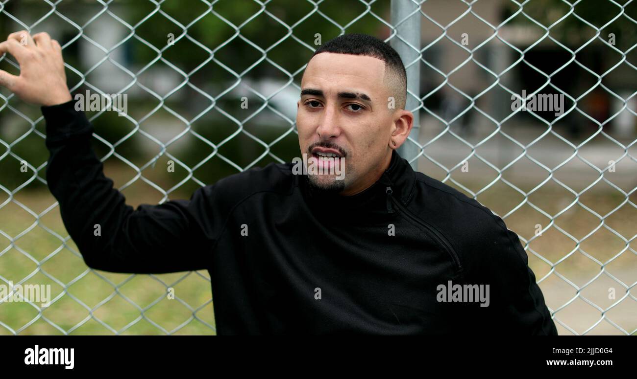 Hispanic guy leaning on metal fence outside. Latino south american ...