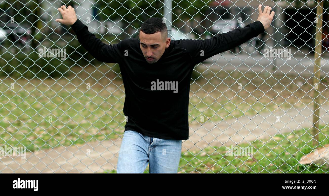 Hispanic guy leaning on metal fence outside. Latino south american ...
