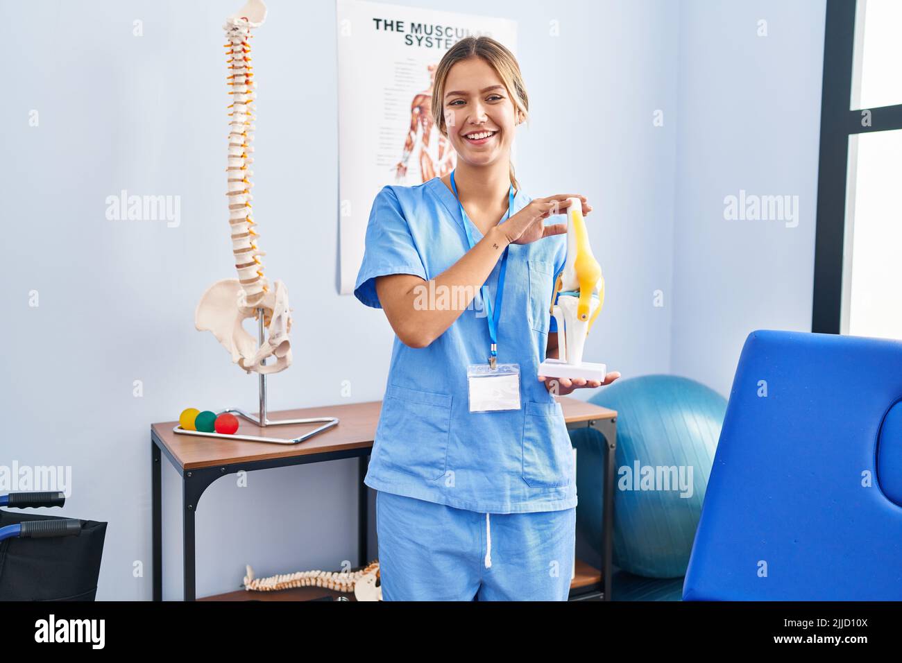 Young blonde orthopedic woman holding anatomical model of knee joint ...