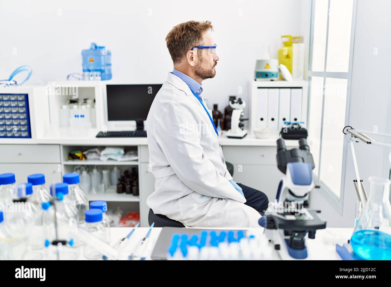 Middle age man working at scientist laboratory looking to side, relax ...