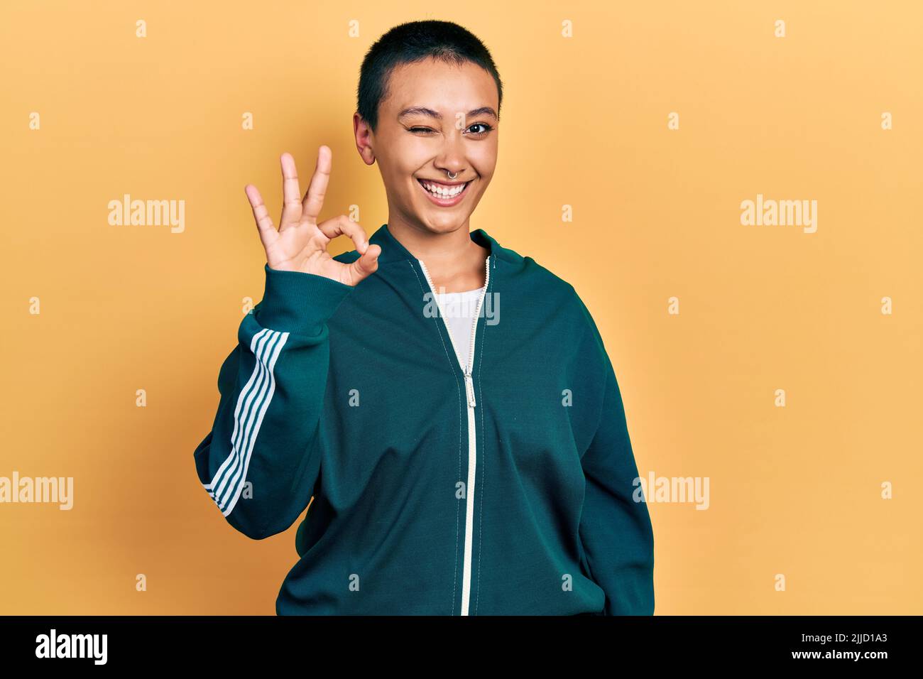 Beautiful hispanic woman with short hair wearing sporty jacket smiling ...