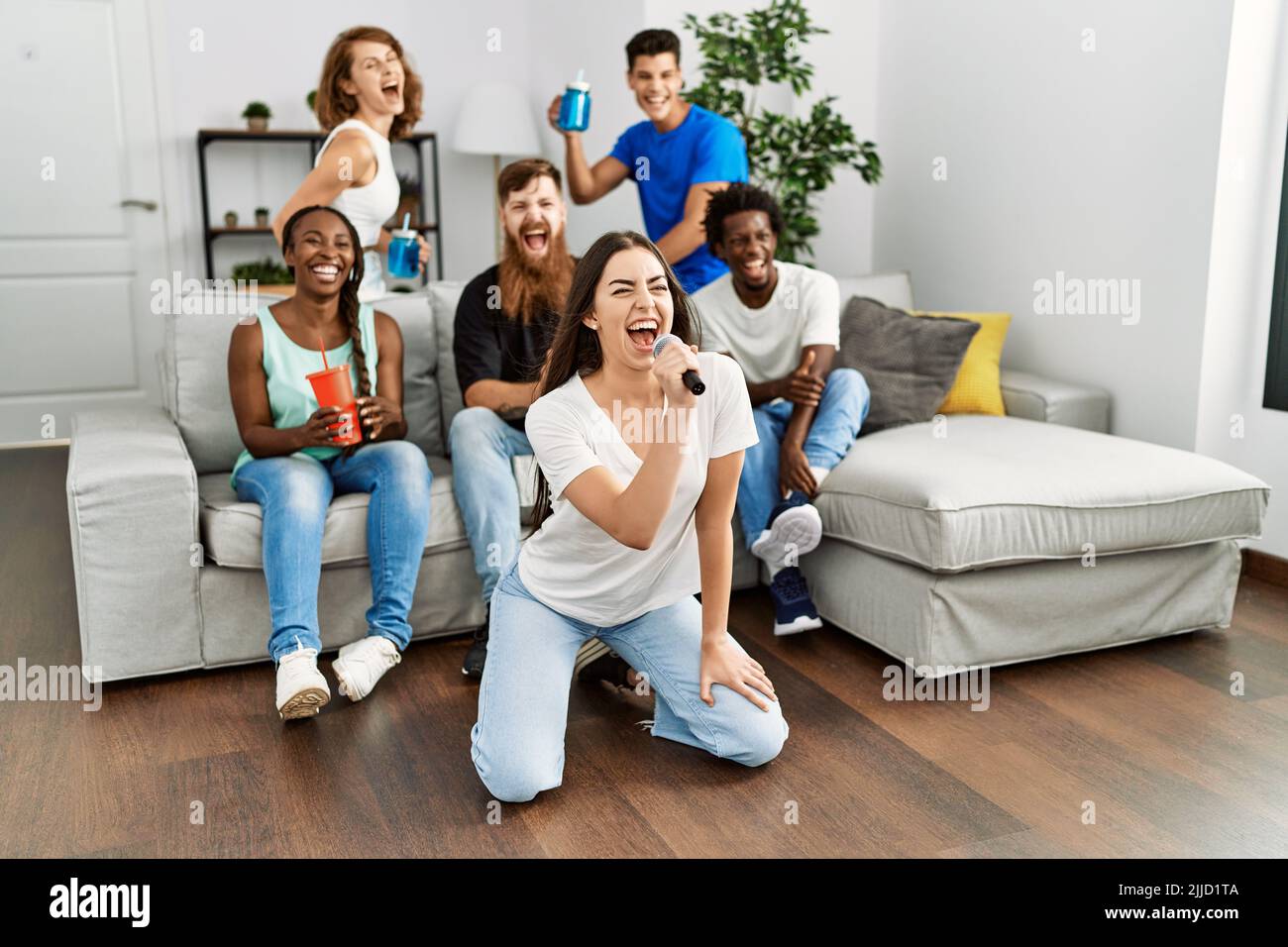Group of young friends having party singing song using microphone at ...