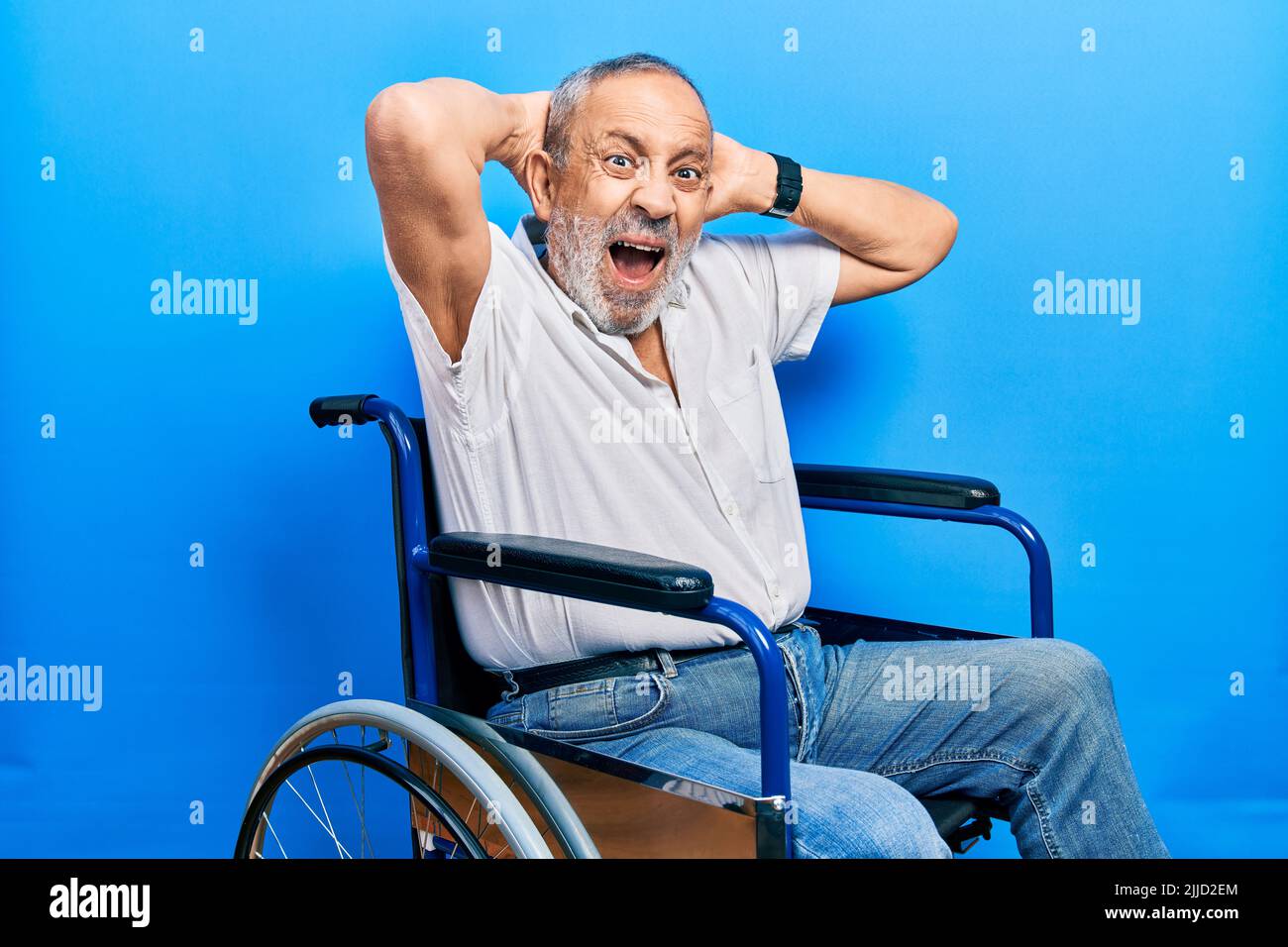 Handsome senior man with beard sitting on wheelchair crazy and scared ...