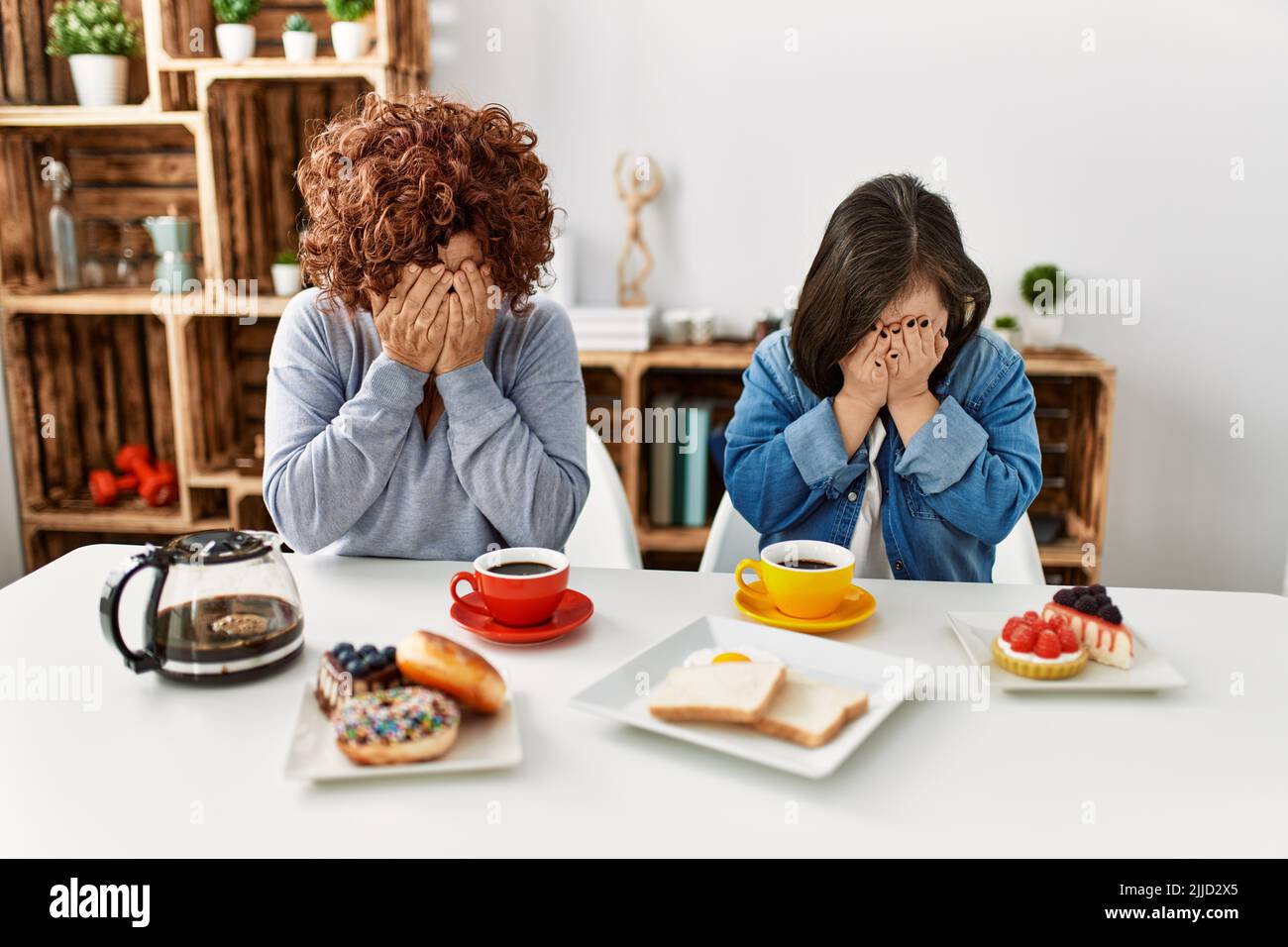 Family of mother and down syndrome daughter sitting at home eating ...