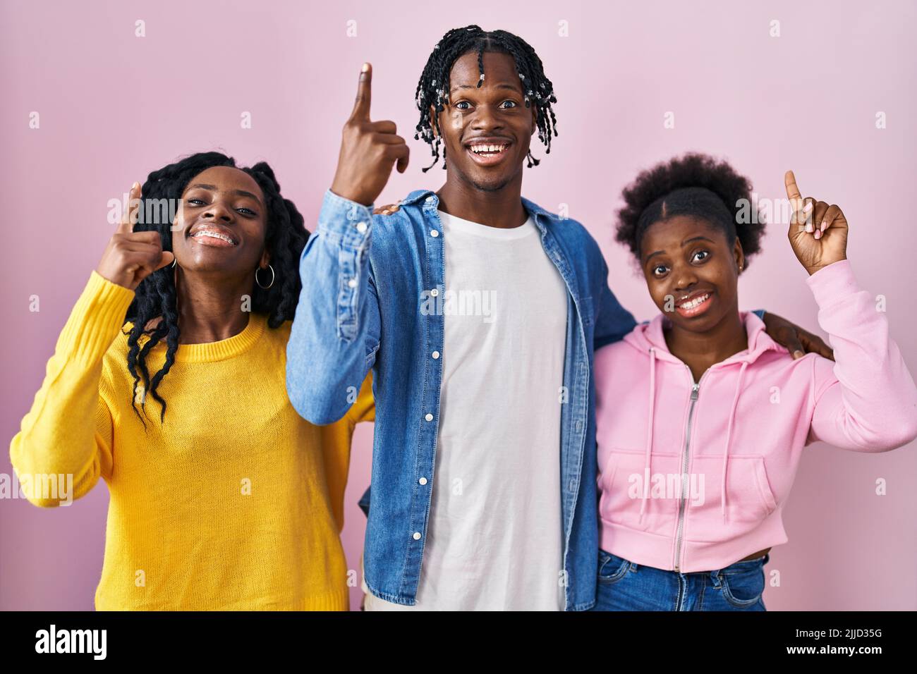 Group of three young black people standing together over pink ...