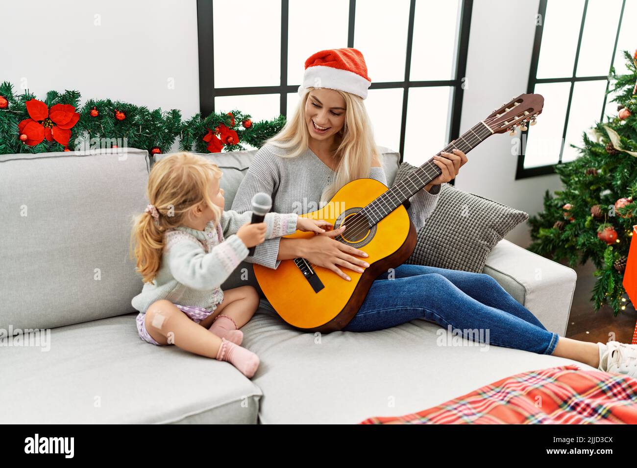 Mother and daughter playing guitar and singing sitting by christmas ...