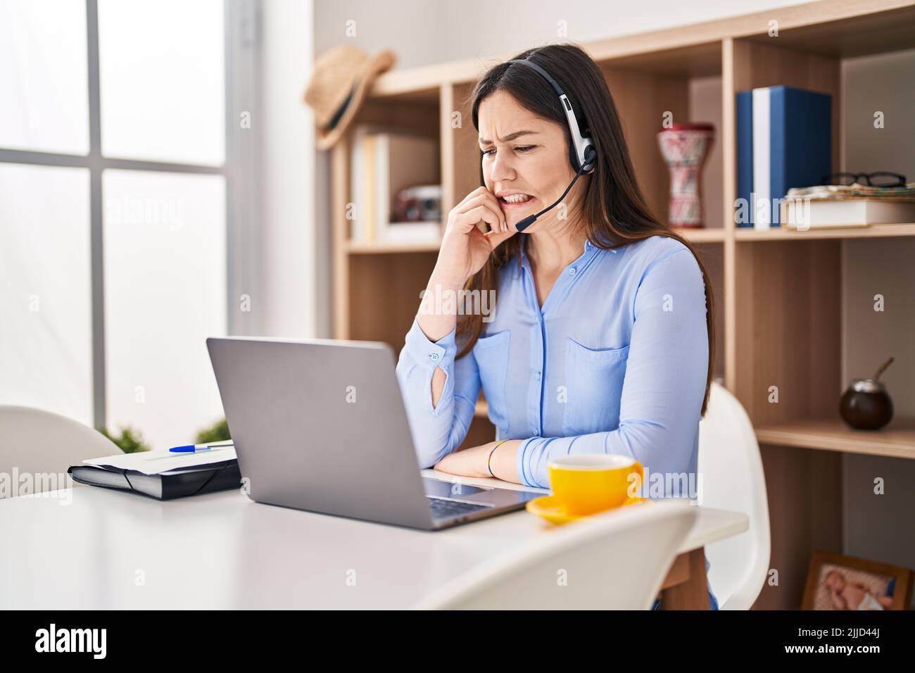 Young brunette woman wearing call center agent headset looking stressed ...
