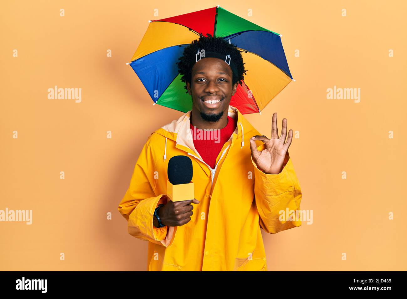 Young african american journalist man wearing yellow raincoat and ...