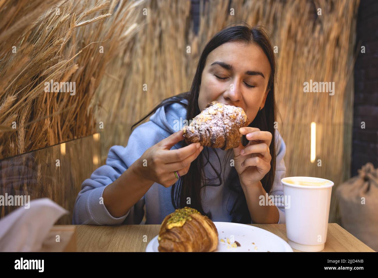 A young woman eats croissants with coffee in a cafe Stock Photo - Alamy