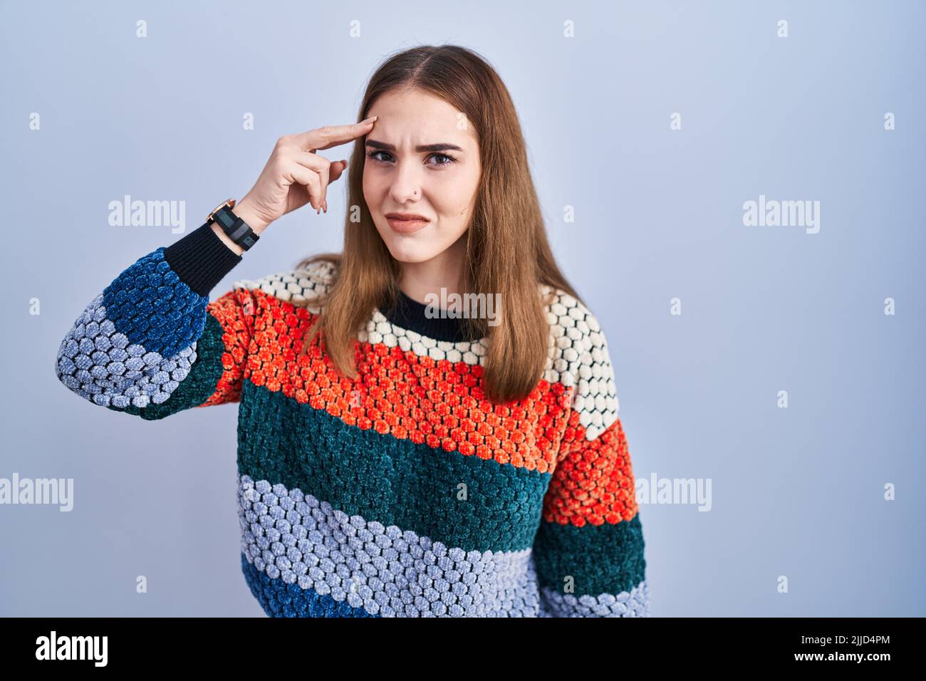 Young hispanic girl standing over blue background pointing unhappy to ...