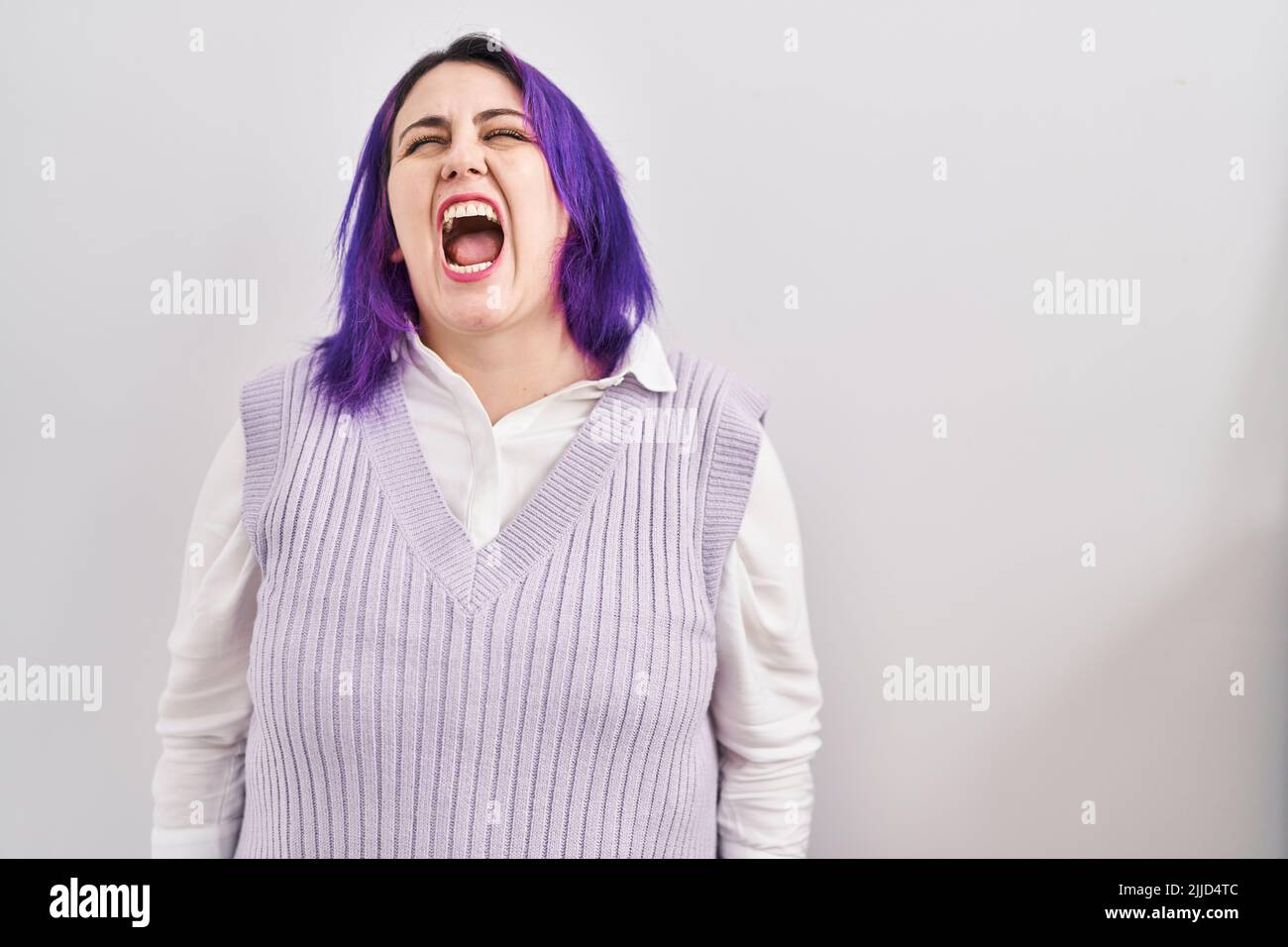 Plus size woman wit purple hair standing over white background angry ...