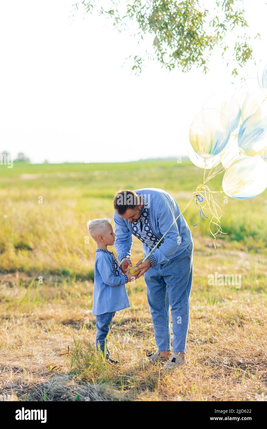 Happy father with his son plays on meadow with air balloons. They are ...