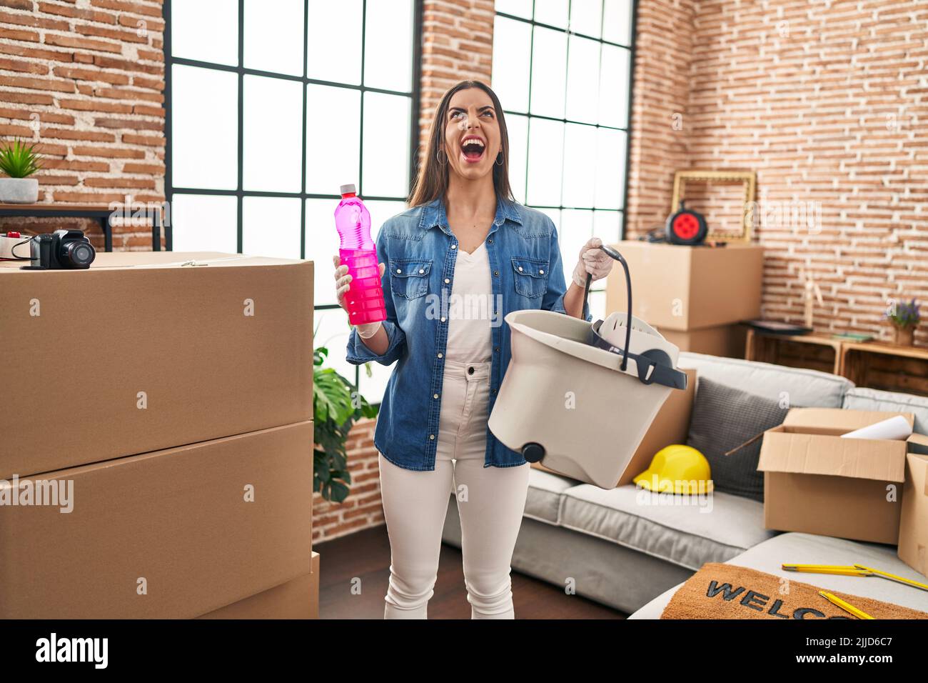 Hispanic woman moving to a new home cleaning the floor angry and mad ...
