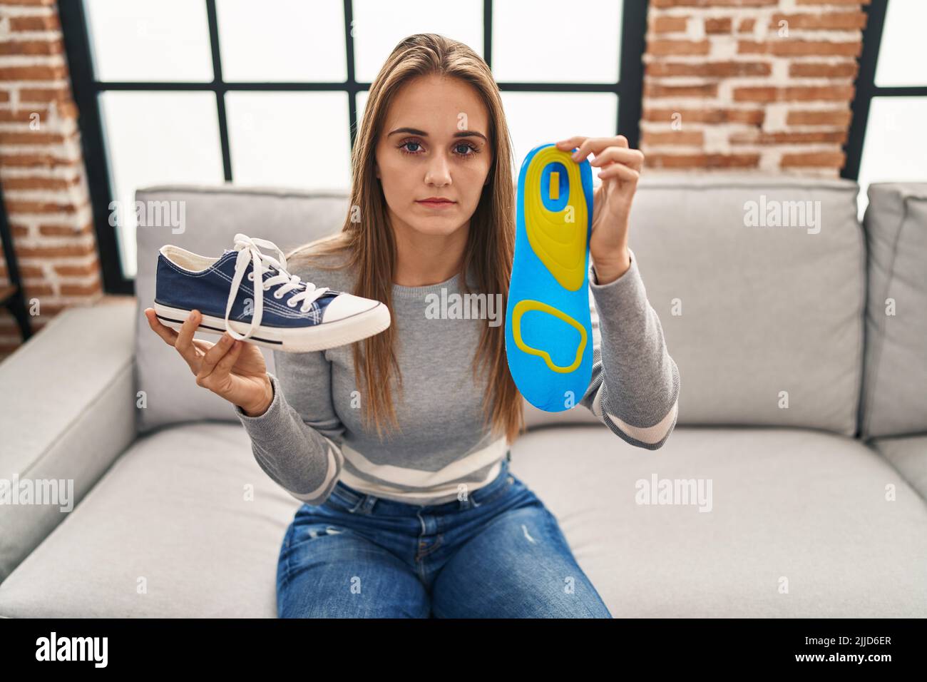 Young woman holding shoe insole depressed and worry for distress ...