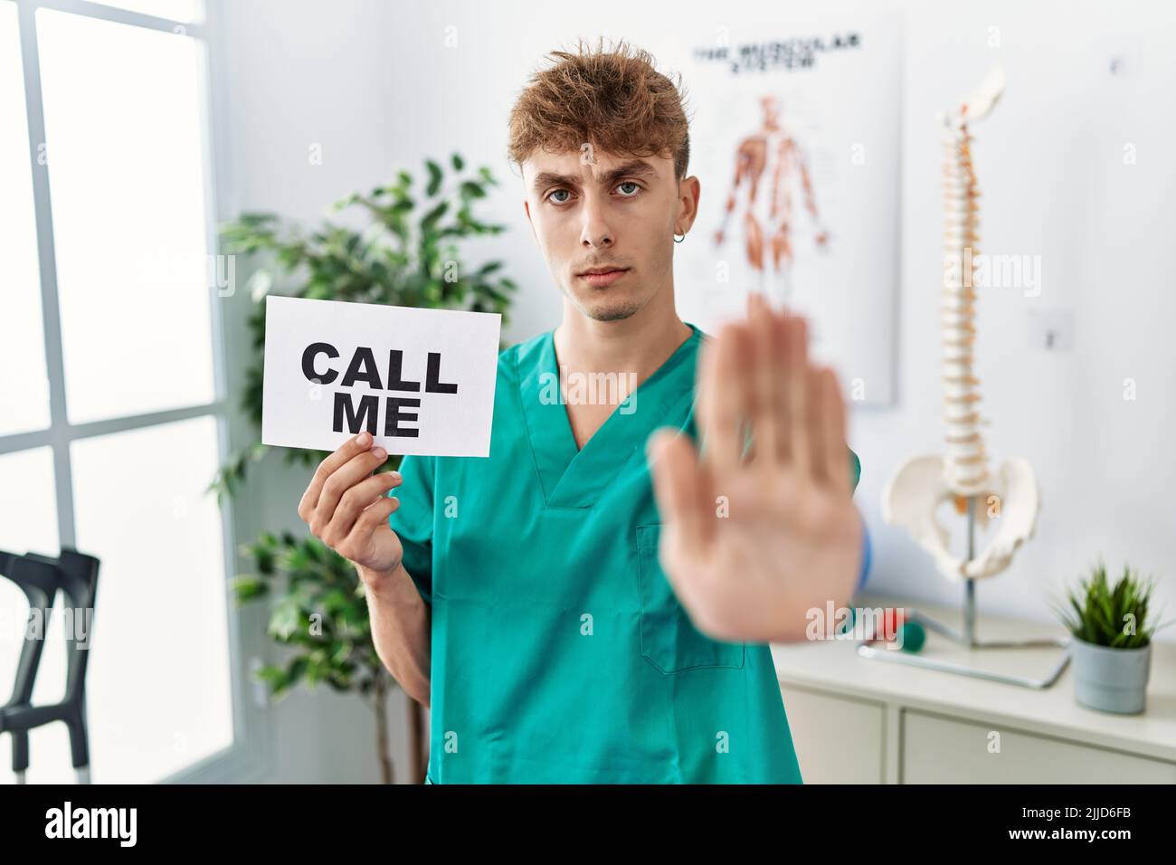 Young caucasian physio man holding call me banner at the clinic with ...