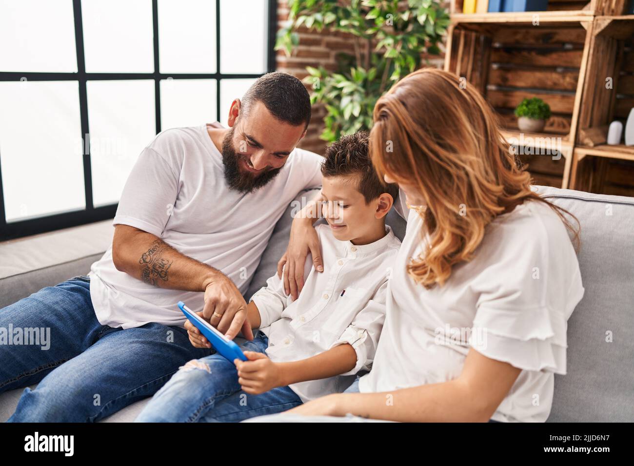 Family using touchpad hugging each other sitting on sofa at home Stock ...