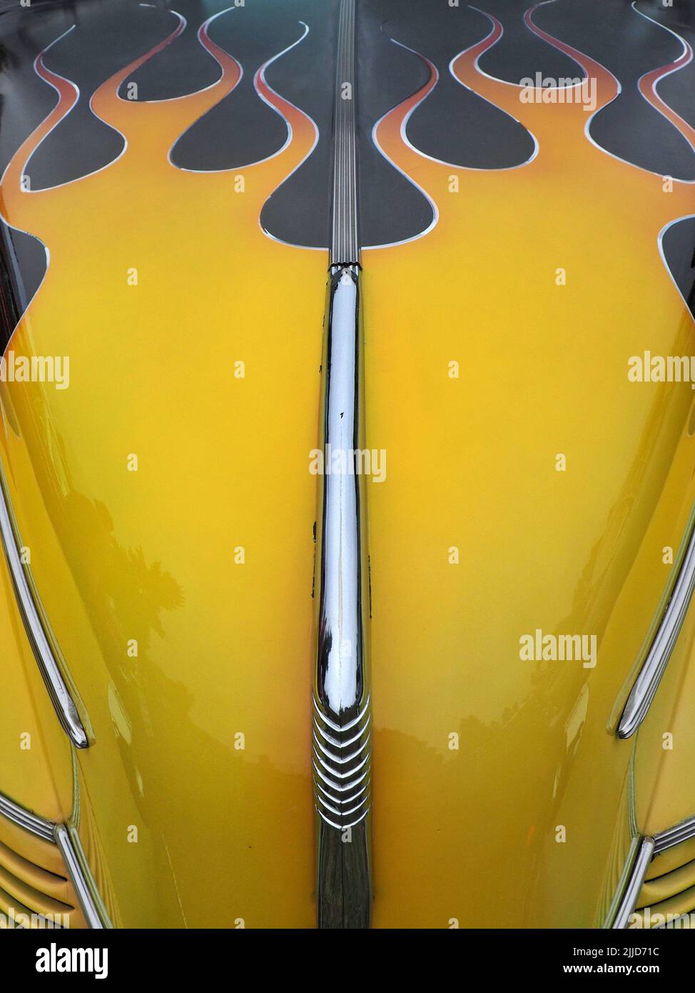 A vertical shot of the front of a yellow Retro car with fire flame ...