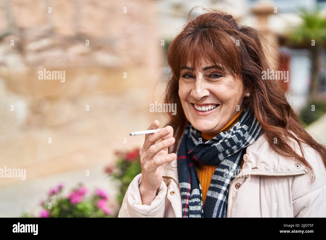 Middle age woman smiling confident smoking cigarette at street Stock ...