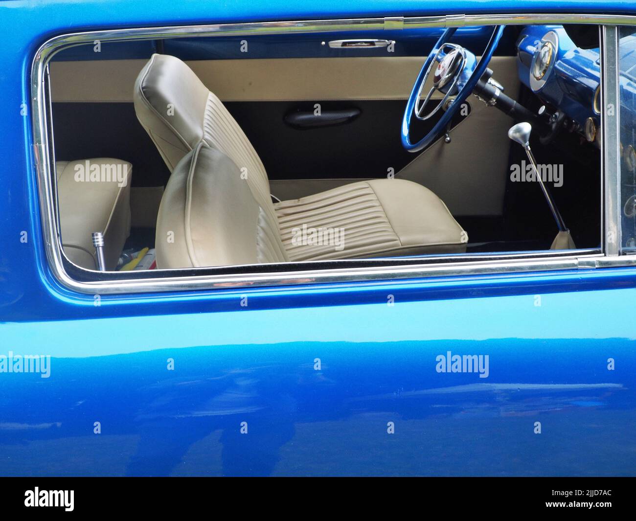 The front seats of a blue retro car through the window with the wheel ...