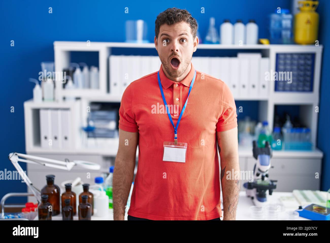 Young hispanic man working at scientist laboratory afraid and shocked ...