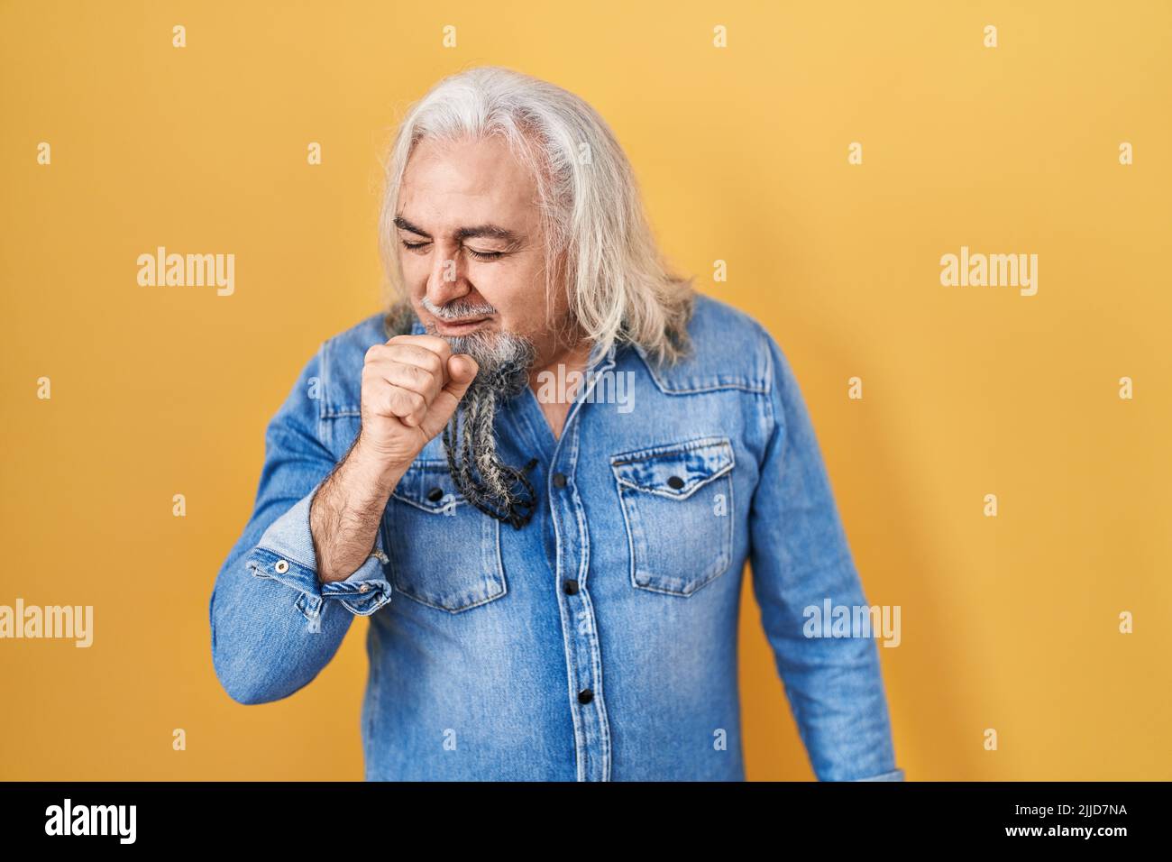 Middle age man with grey hair standing over yellow background feeling ...
