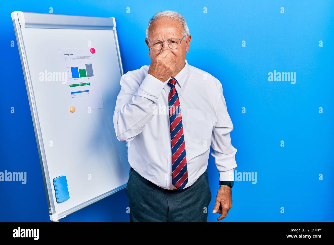 Senior man with grey hair standing by business blackboard smelling ...