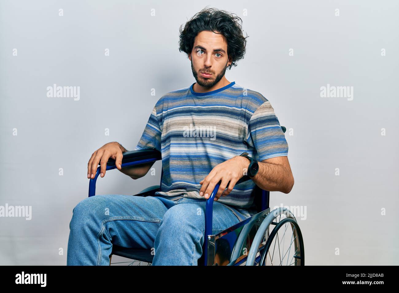 Handsome hispanic man sitting on wheelchair depressed and worry for ...