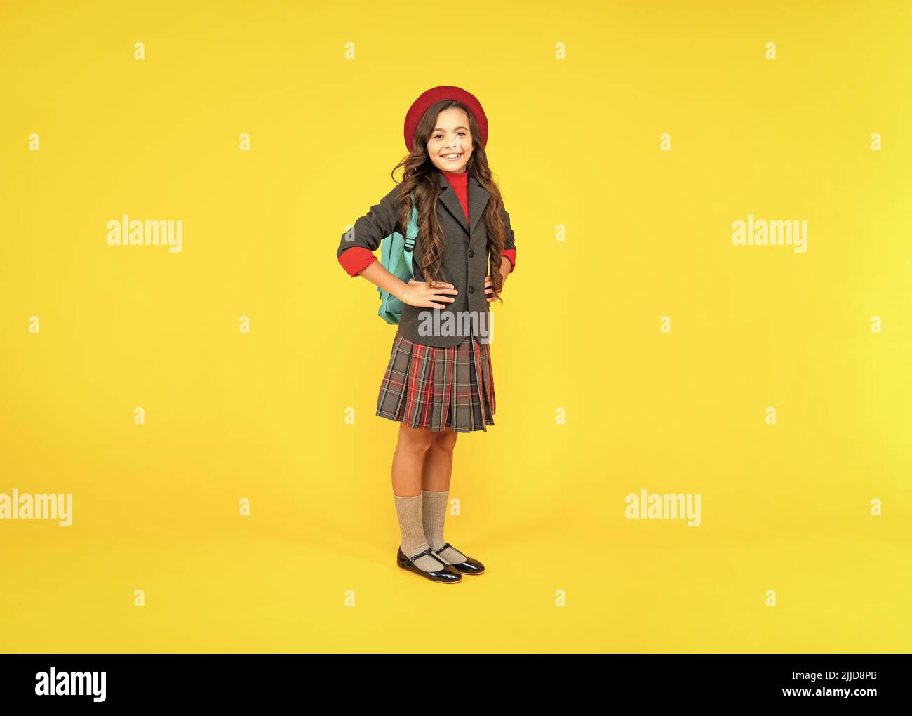 smiling teen girl in uniform and beret with school bag on yellow ...