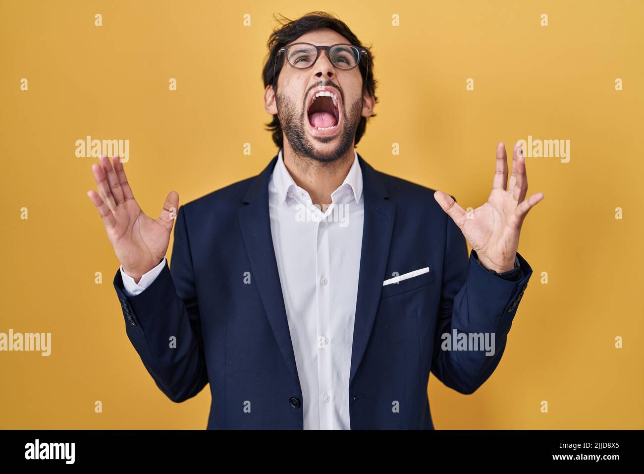 Handsome latin man standing over yellow background crazy and mad ...