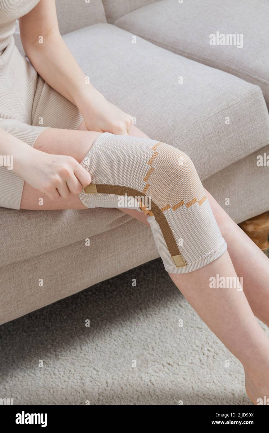 Knee support brace on a woman leg. girl in an orthosis in the interior ...