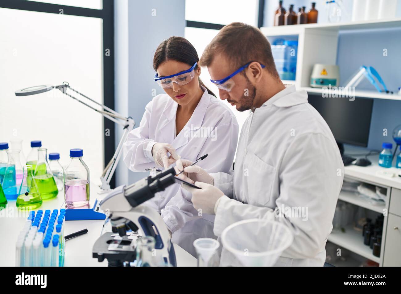 Man and woman scientist partners write on clipboard measuring liquid ...