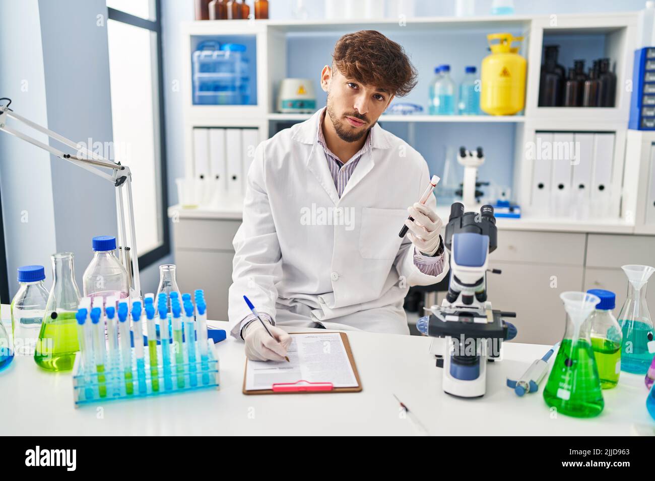 Young arab man scientist write on document analysing blood test tube at ...